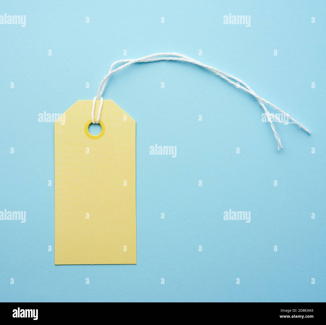 empty yellow paper tag tied with white string. Price, gift, sale tag on ...