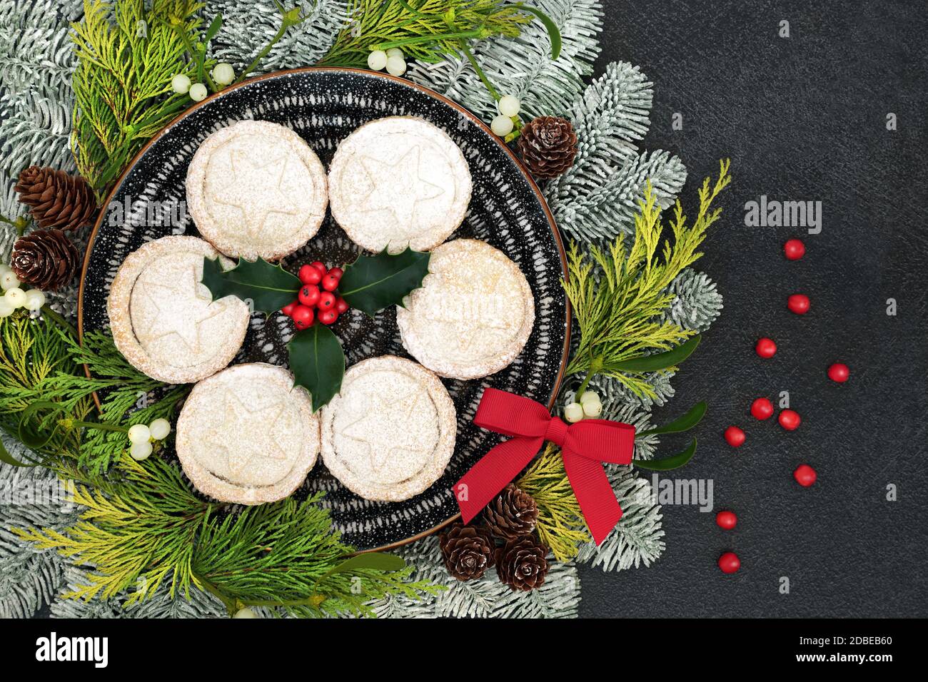 Festive homemade Christmas mince pies on a plate with holly, snow ...