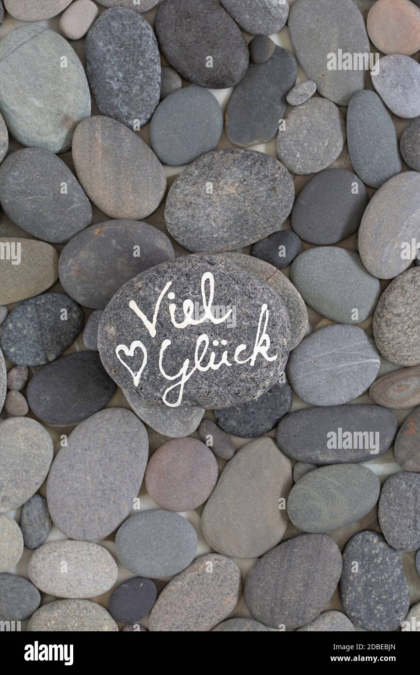 smooth grey pebble with white handwritten german text for good luck ...