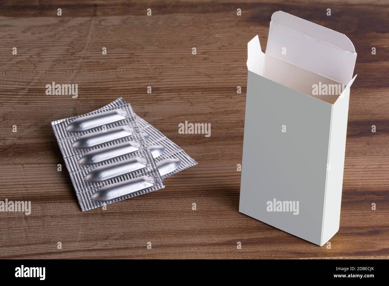 Suppositories loafs and an empty box on wooden table background ...