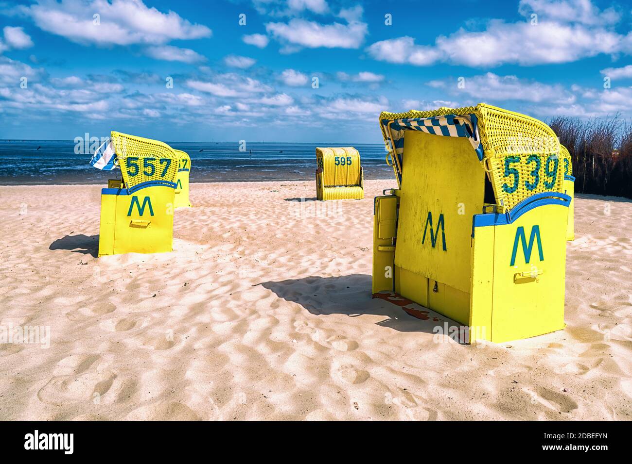 Yellow beach chairs by the sea stand in the sand in the midday sun ...
