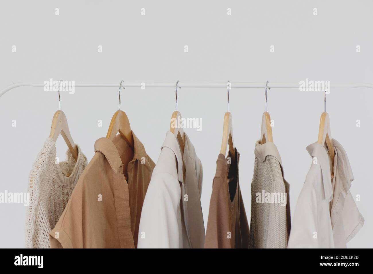 Collection of female clothes hanging on a rack on white background ...