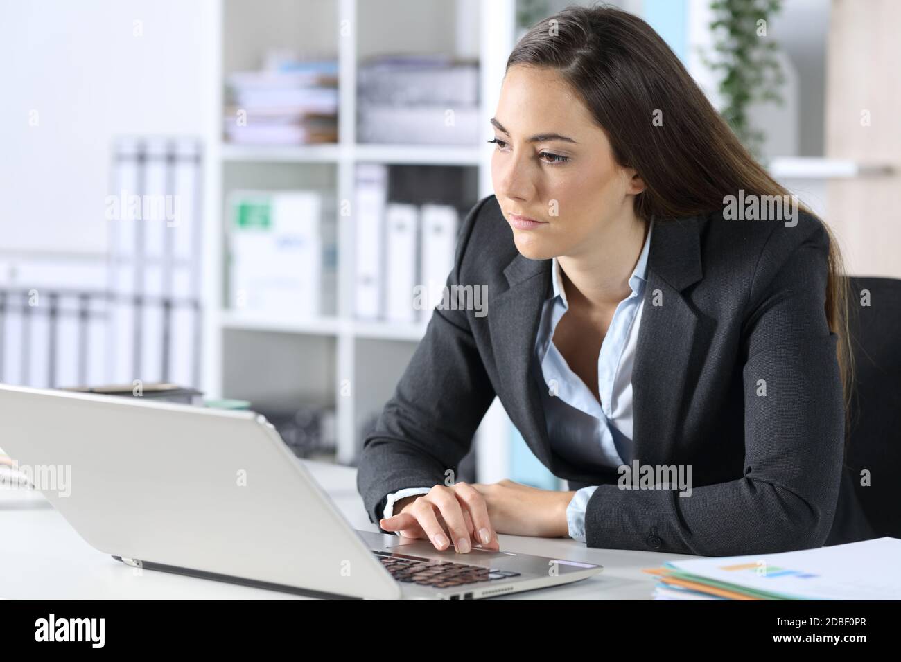 Distracted executive woman with laptop looking away sitting on her desk ...