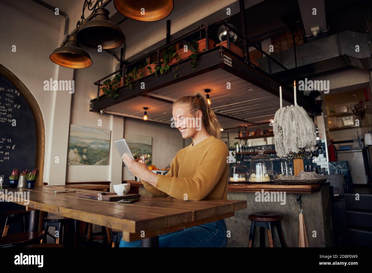 Beautiful smiling business woman sitting in cafe using digital tablet ...