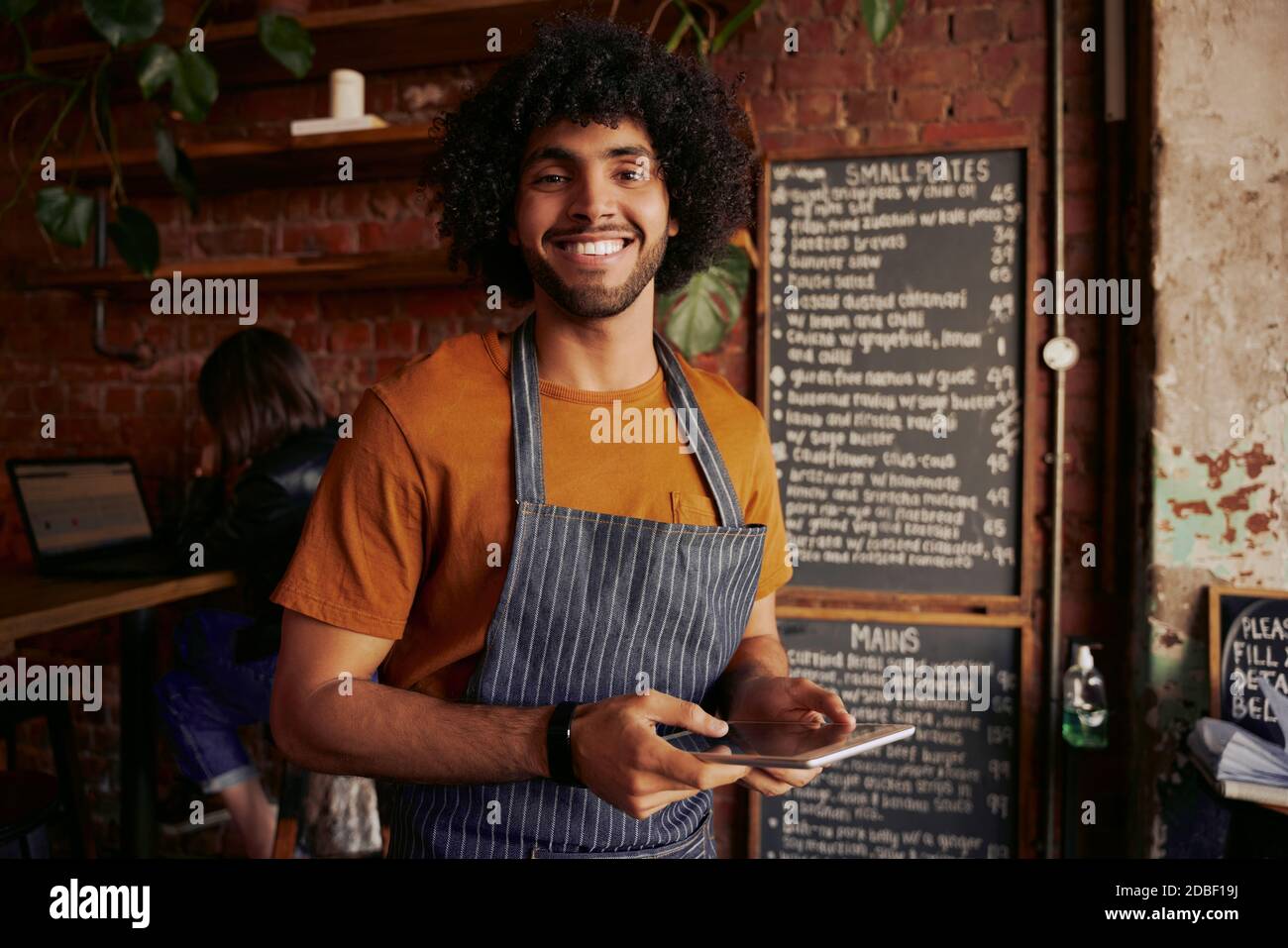Successful small cafe business owner wearing apron using digital tablet ...