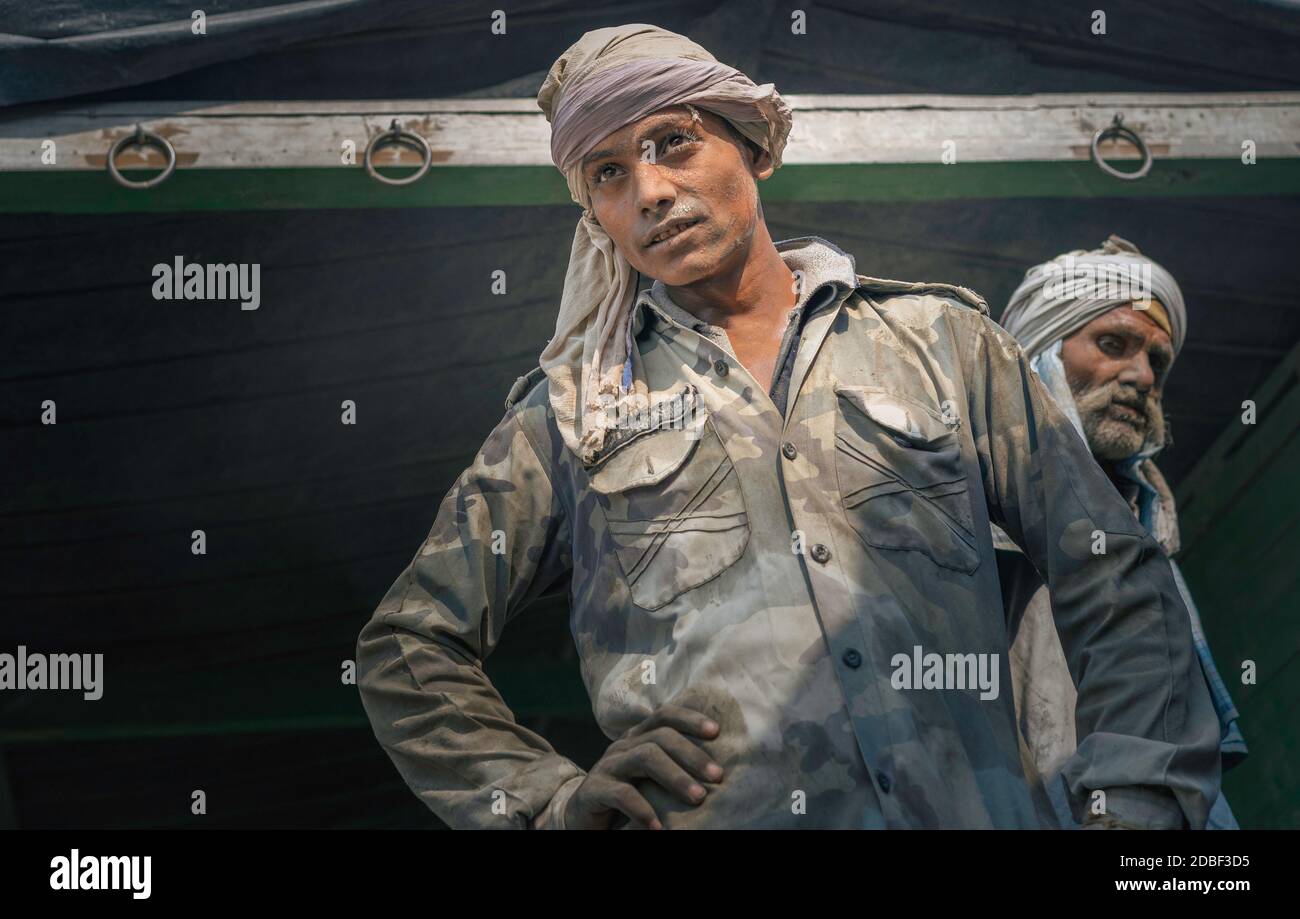 Manual worker employed to move heavy bags of cement from railway train ...