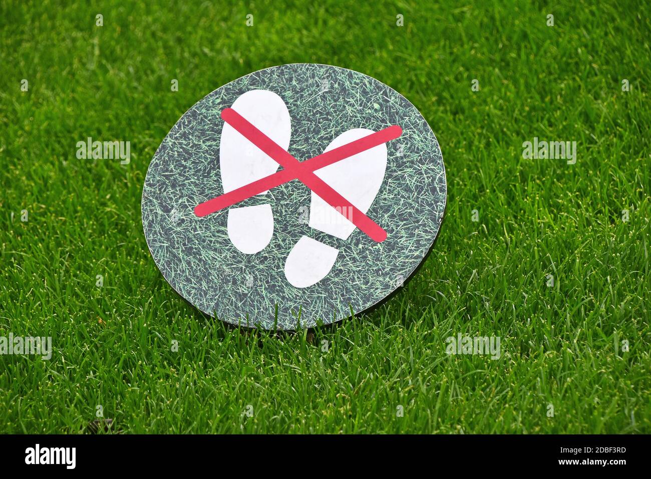 Close up keep off the grass warning sign over green lawn background ...