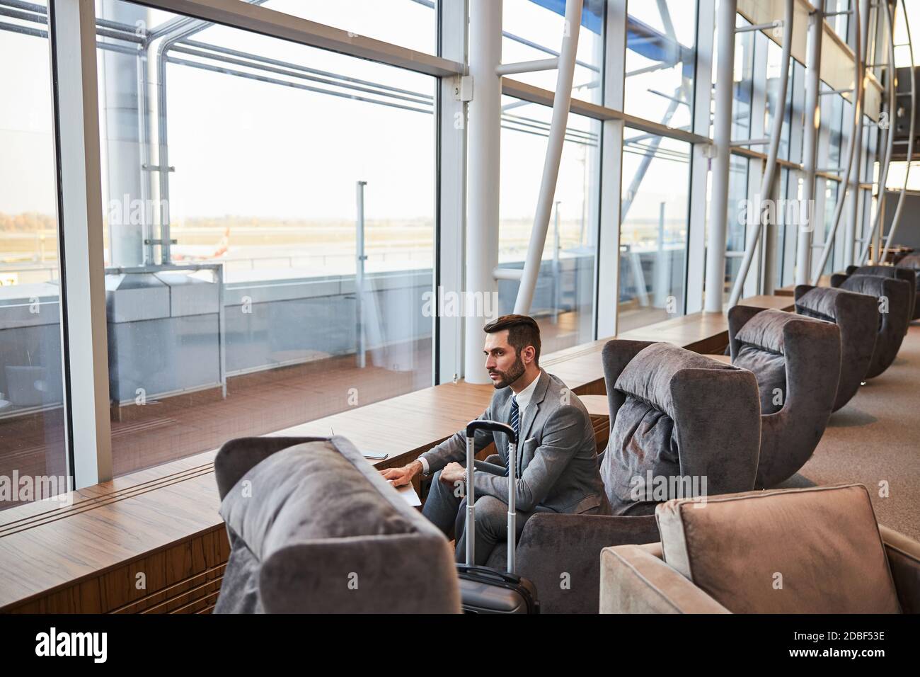 Man leaning over a table from a cozy armchair Stock Photo - Alamy