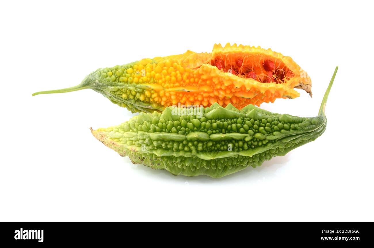 Two ripe bitter melons - green and overripe orange, split open with red ...
