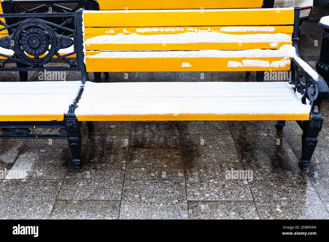 front view of yellow wooden benches under snow on Manezhnaya square in ...