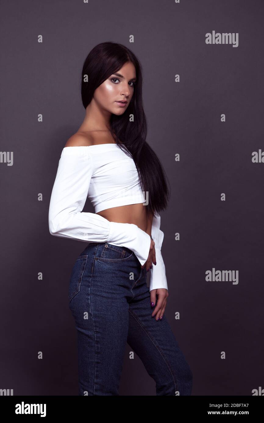 A model posing in a studio wearing jeans and a crop top. Stock Photo ...