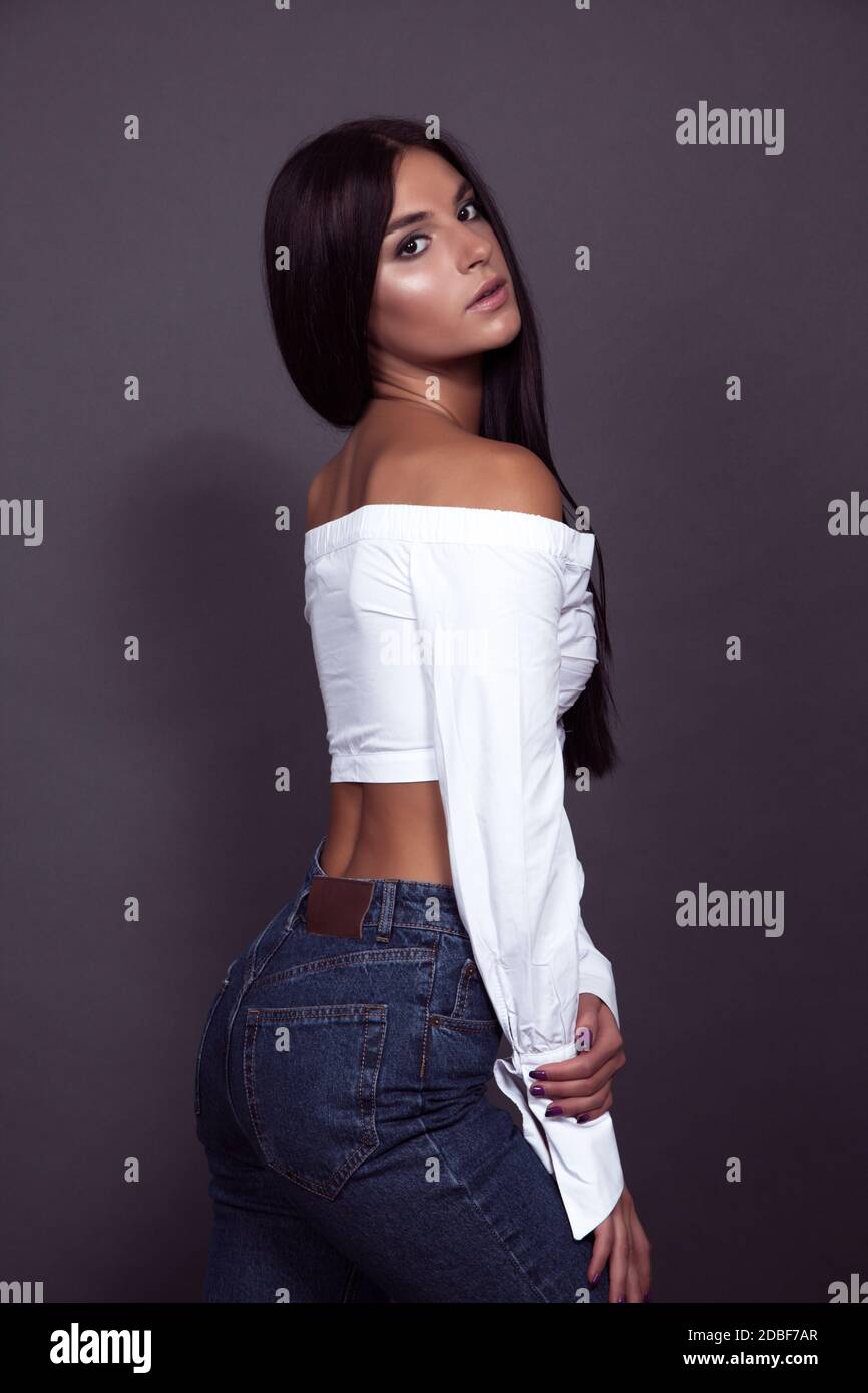 A model posing in a studio wearing jeans and a crop top. Stock Photo ...