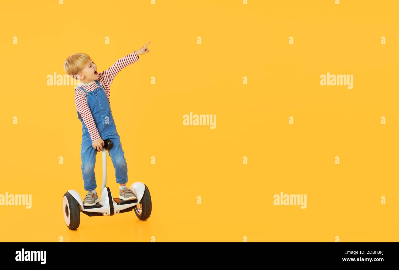 Funny child boy boy riding on hoverboard or gyroscooter on yellow ...