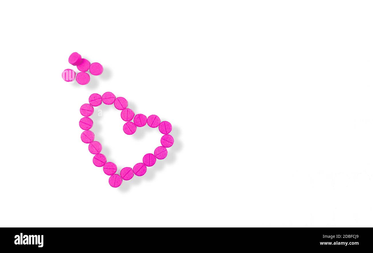 Pink tablets are arranged in a heart shape isolated on white background ...