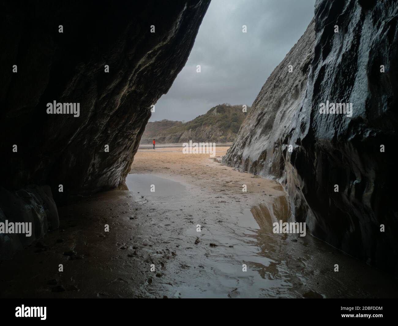 A small cave looking out to the sand Caswell Bay Beach in Gower, Wales ...