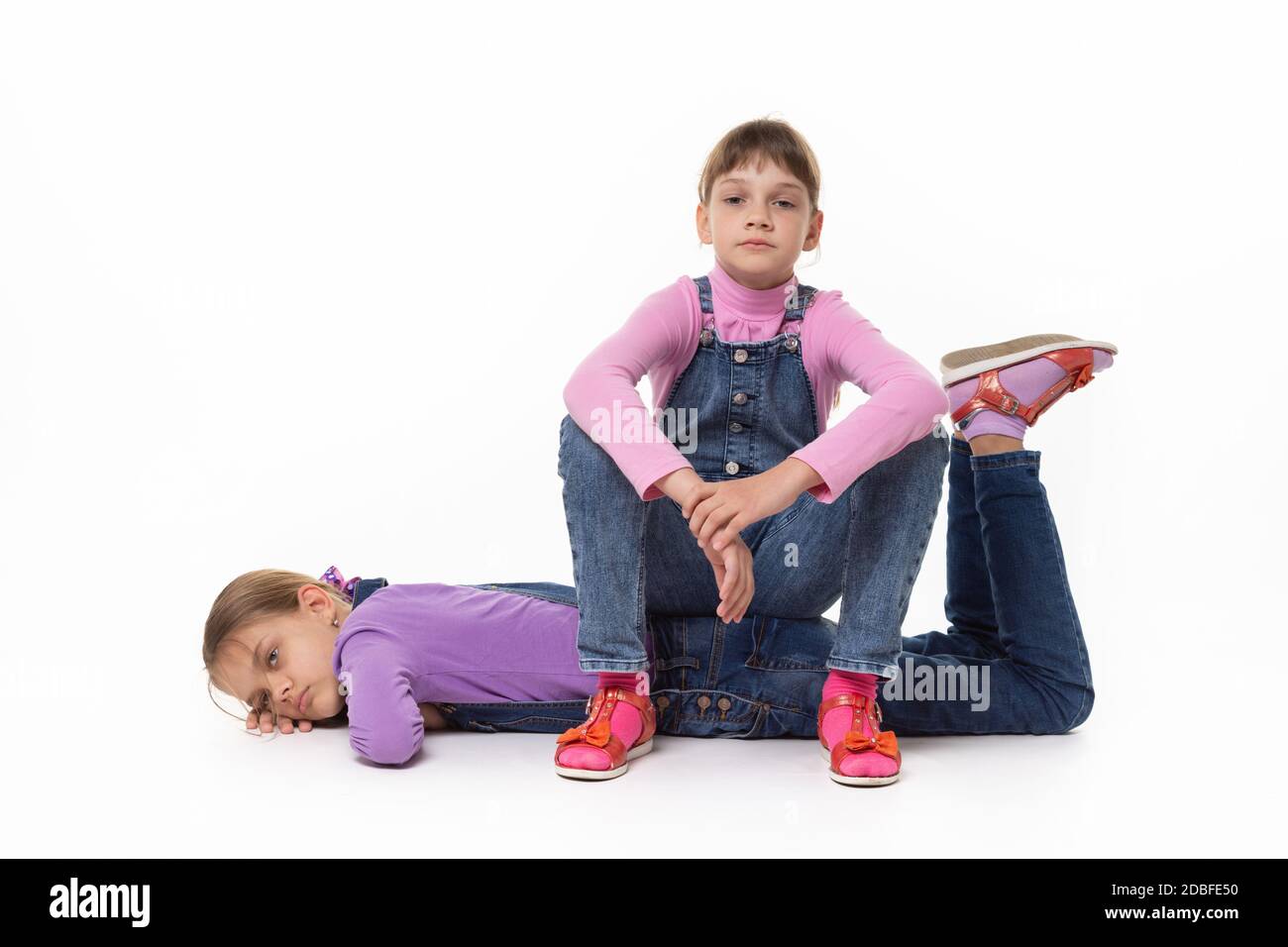 Two sad girls rest sitting and lying on a white background Stock Photo ...