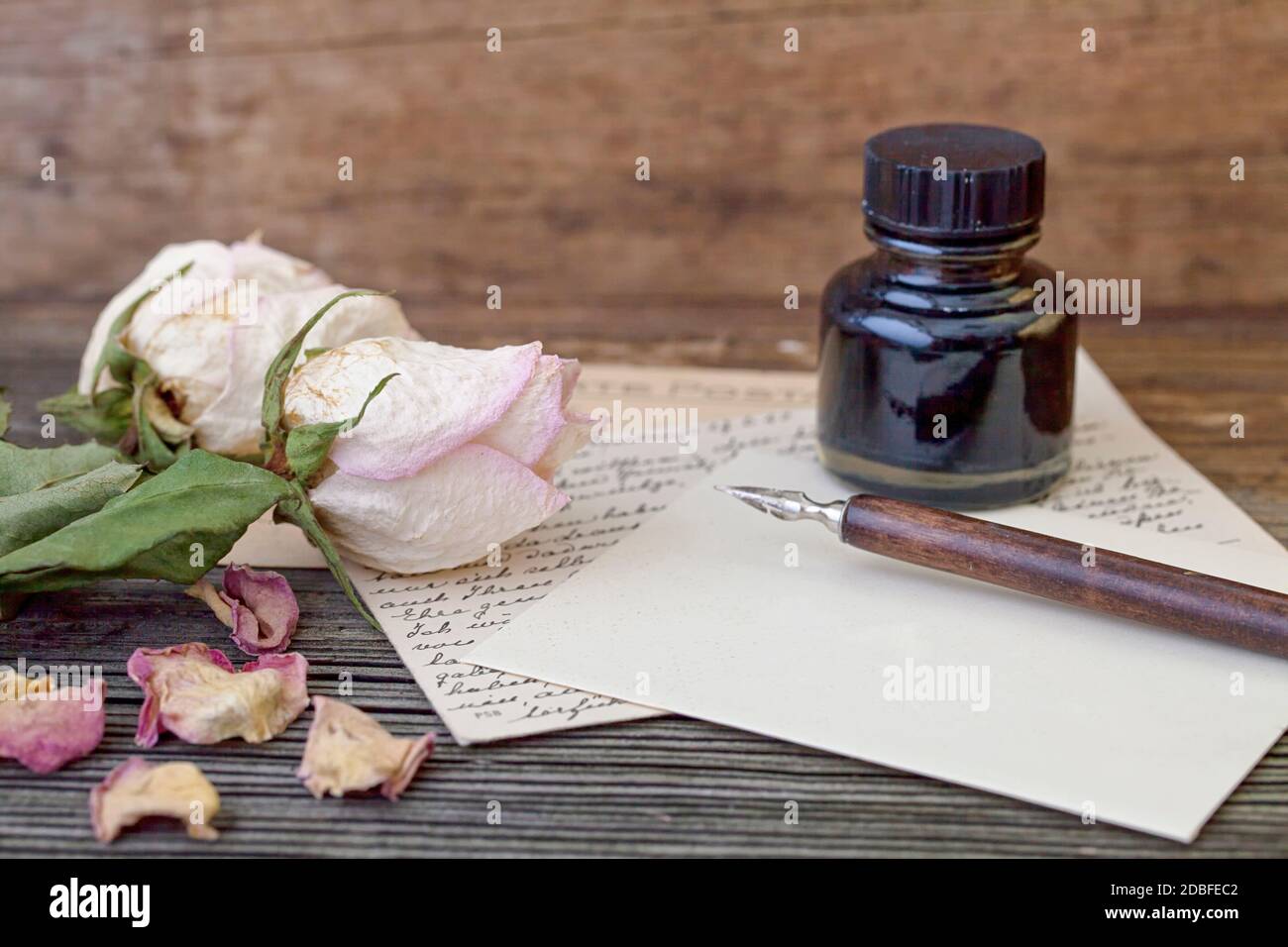 Nostalgic still life with vintage pen, ink bottle, dry roses and ...