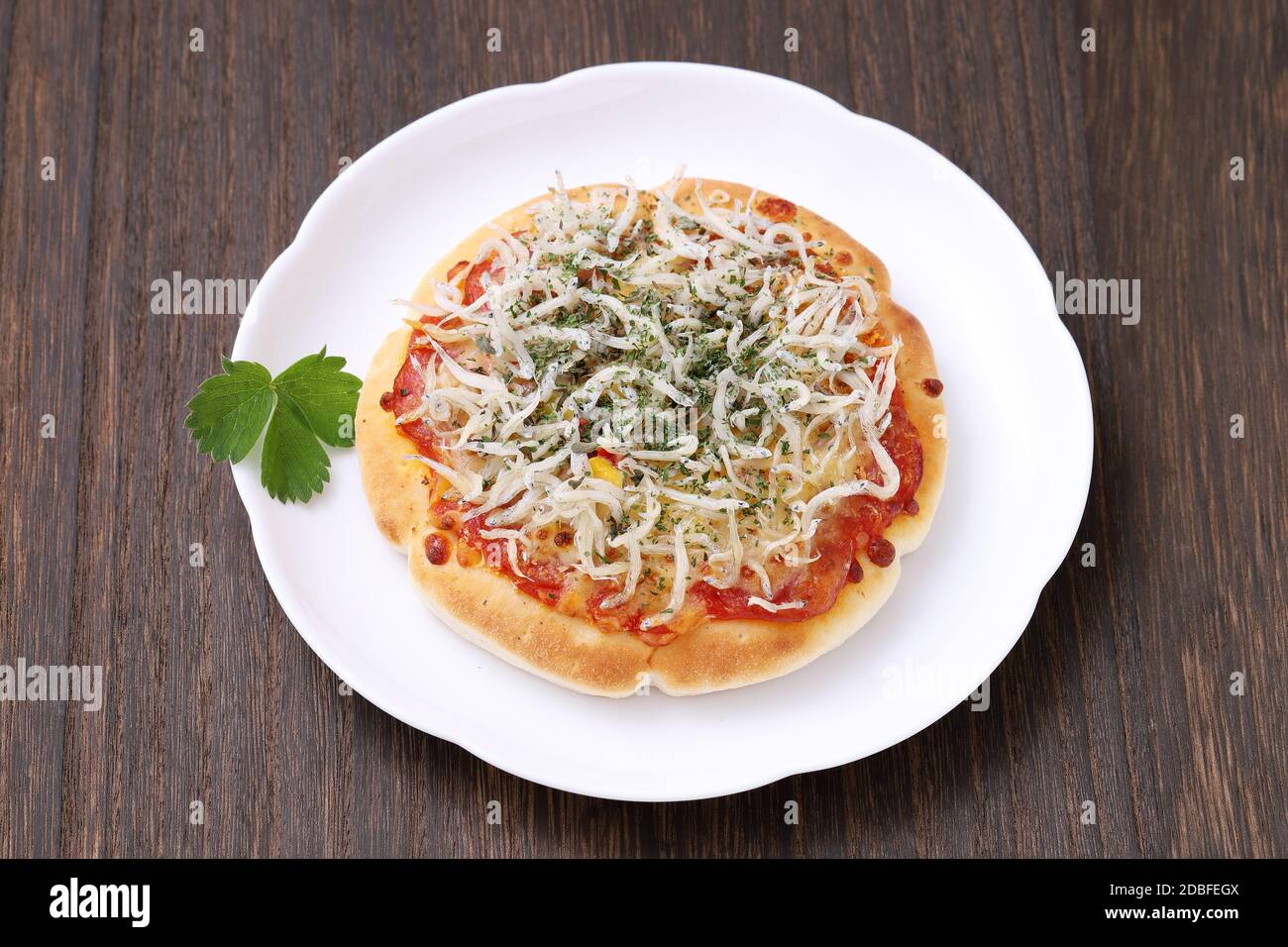 small fish shirasu pizza on a plate with wooden table Stock Photo - Alamy