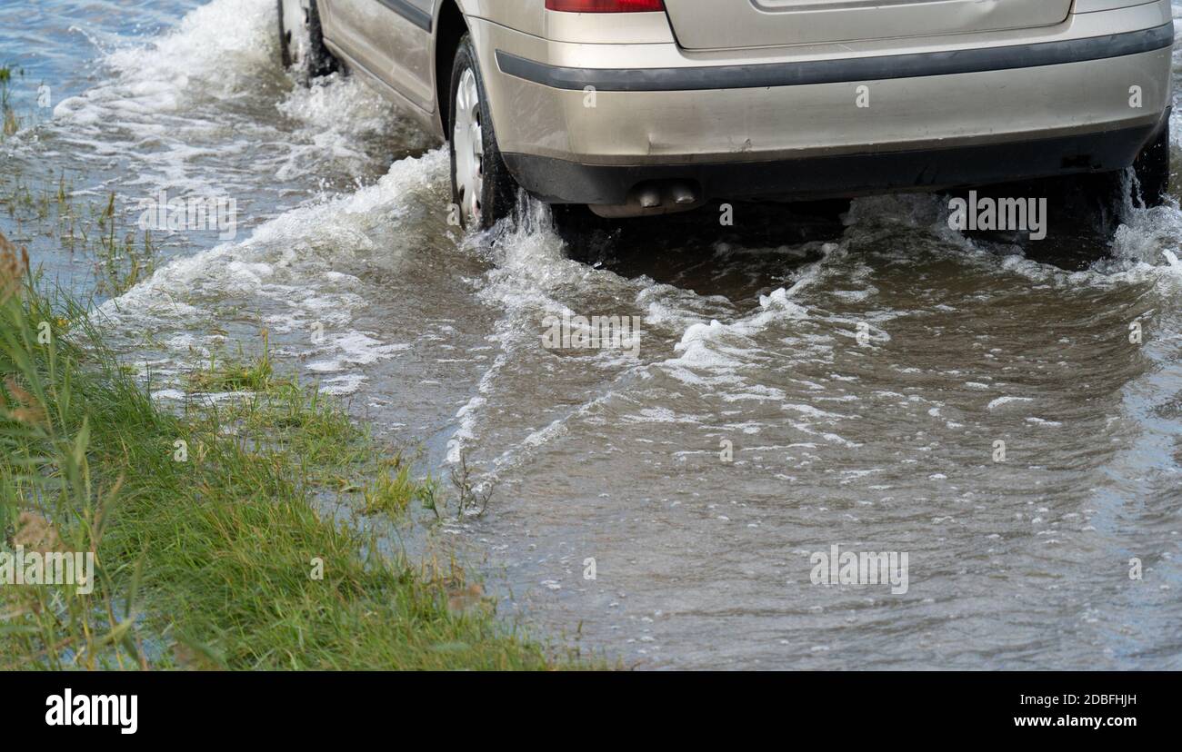 Car driving over flooded road after the storm Stock Photo - Alamy