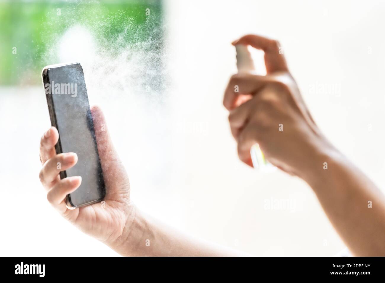 close-up cleaning mobile phone using alocohol spray from bottle ...