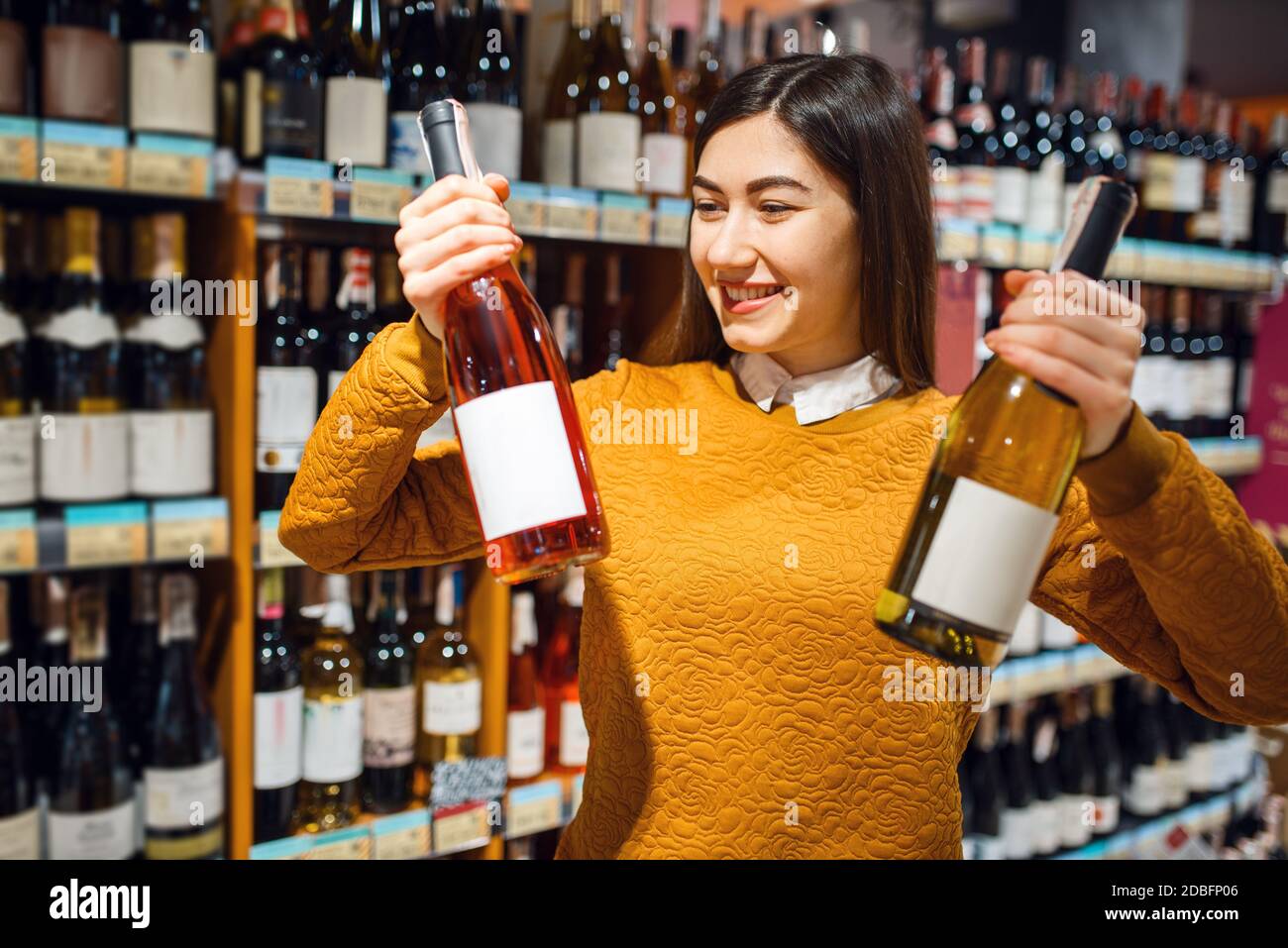 Woman with two bottles of alcohol in grocery store. Male person buying ...