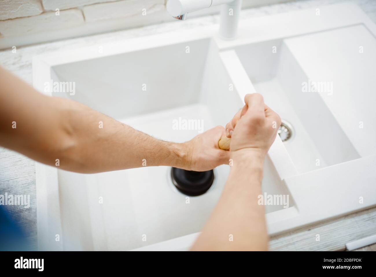 Male plumber in uniform holds plunger, problem with clog in the kitchen ...