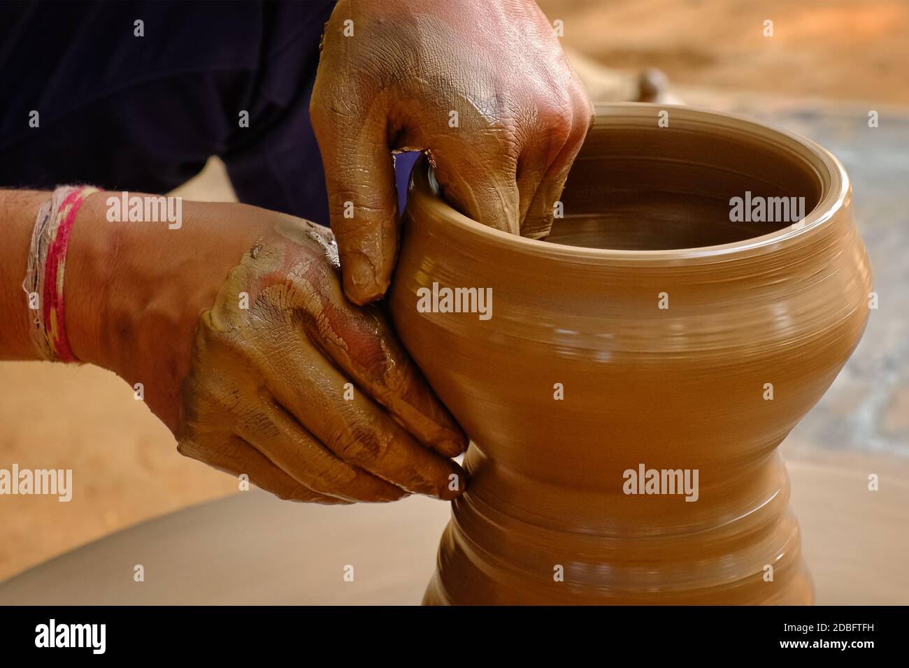 Pottery - skilled wet hands of potter shaping the clay on potter wheel ...