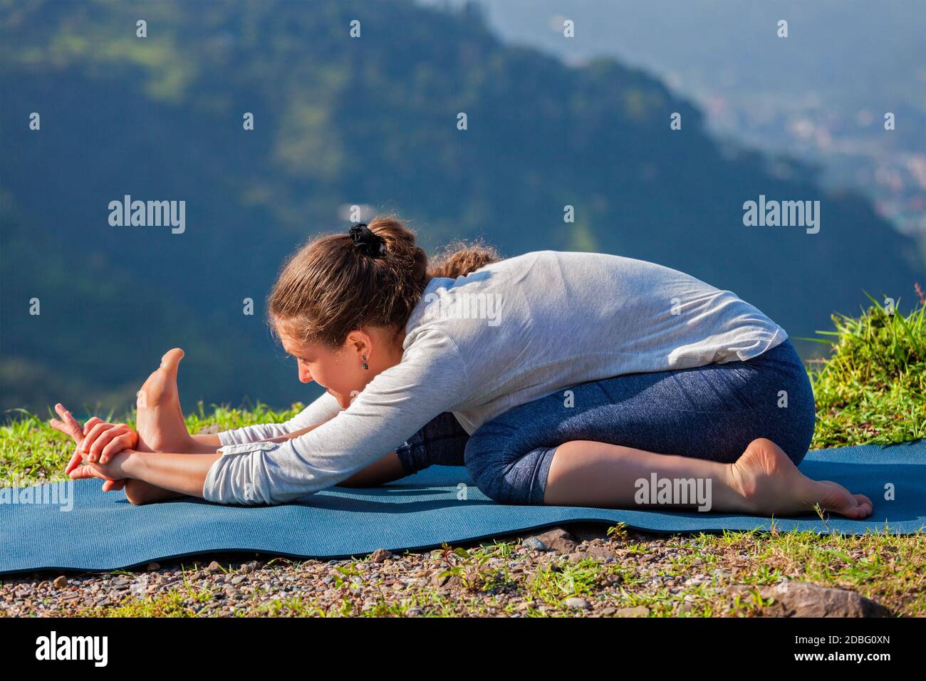 Yoga outdoors - woman doing Ashtanga Vinyasa yoga Tiryam-Mukha Eka-Pada ...