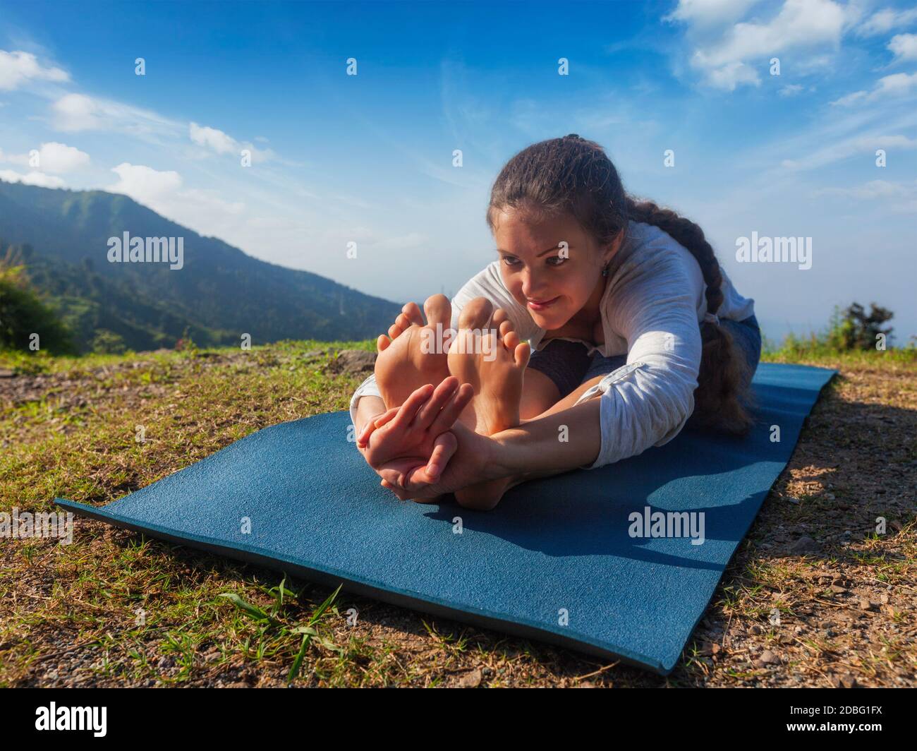 Woman doing Ashtanga Vinyasa Yoga asana Paschimottanasana seated ...
