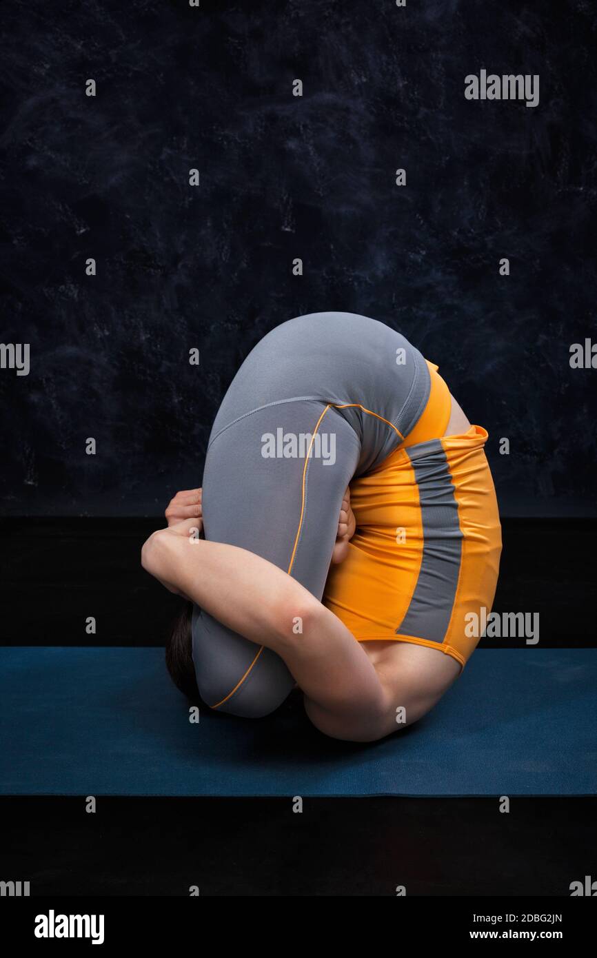 Woman doing Hatha Yoga Ashtanga Vinyasa yoga asana Garbha pindasana ...