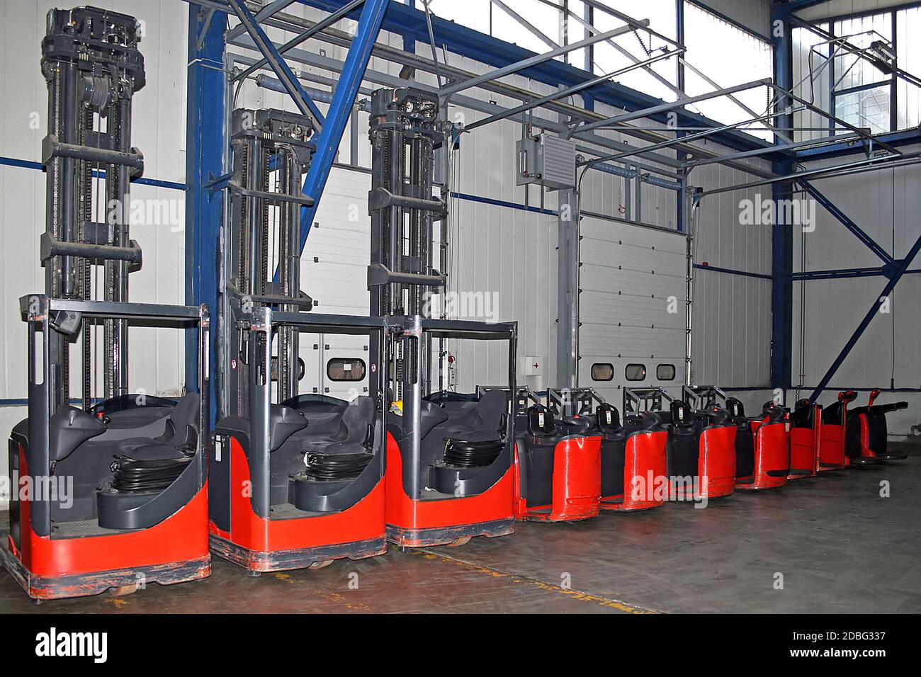 Red fork lifter trucks and carriers in warehouse Stock Photo - Alamy