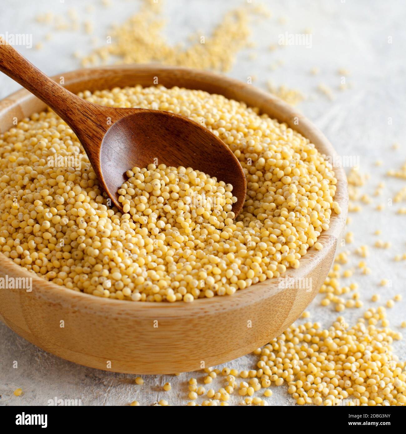 Raw dry hulled millet in a wooden bowl with a spoon with a copy space ...