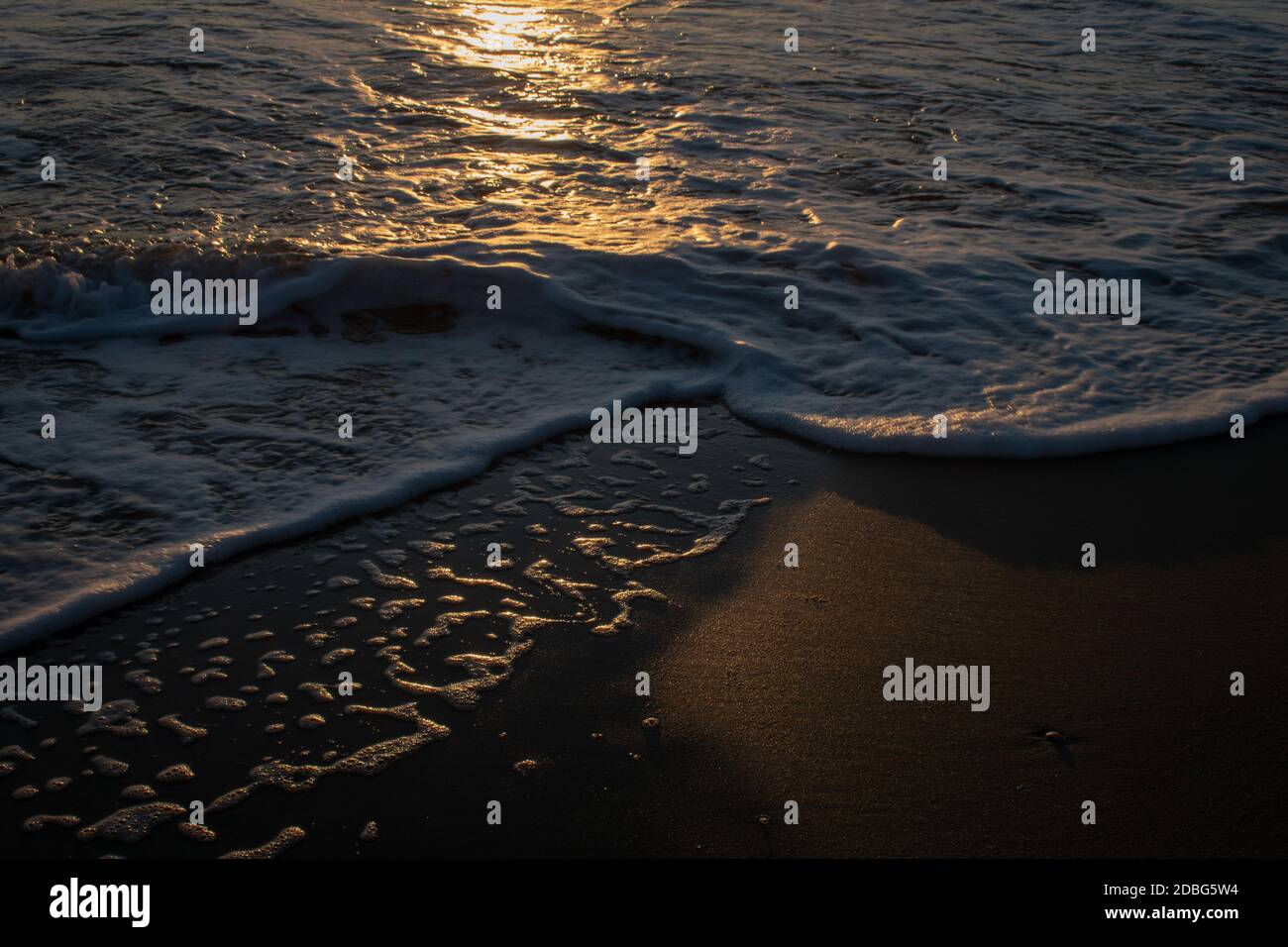 Sunset at the beach with reflection and waves Stock Photo - Alamy
