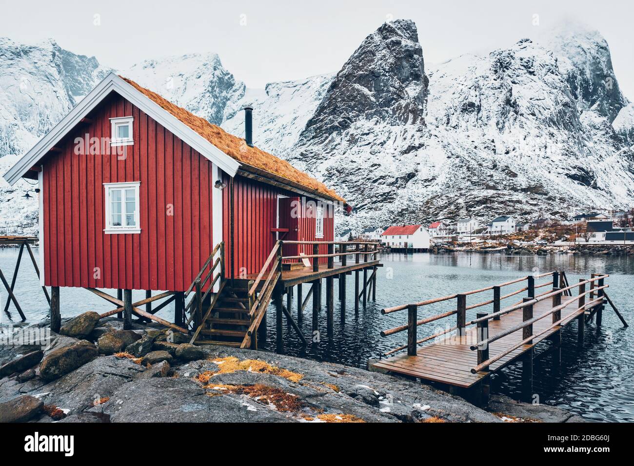 Traditional red rorbu house with grass covered roof in Reine village on ...