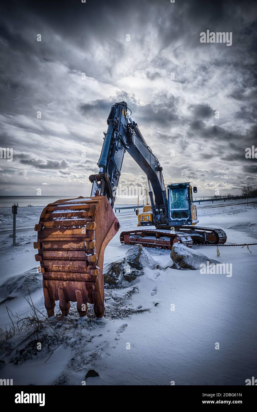 Old excavator with excavator bucket in winter. Road construction in ...