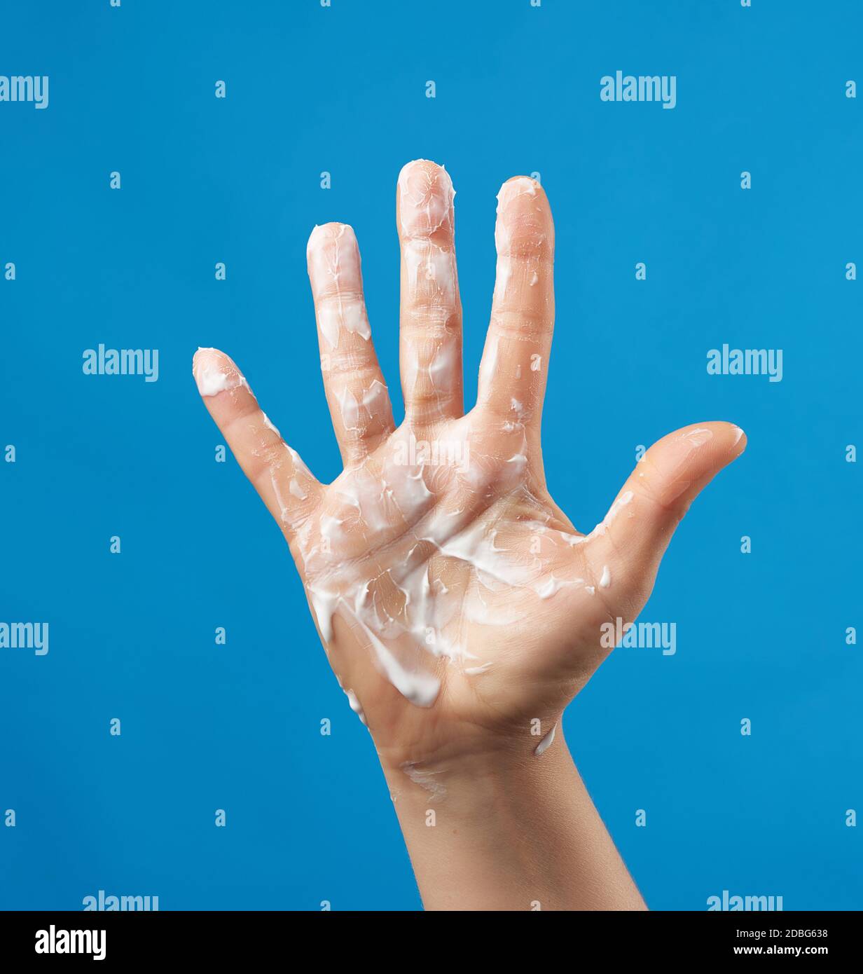 open female palm smeared with white cream on a blue background ...