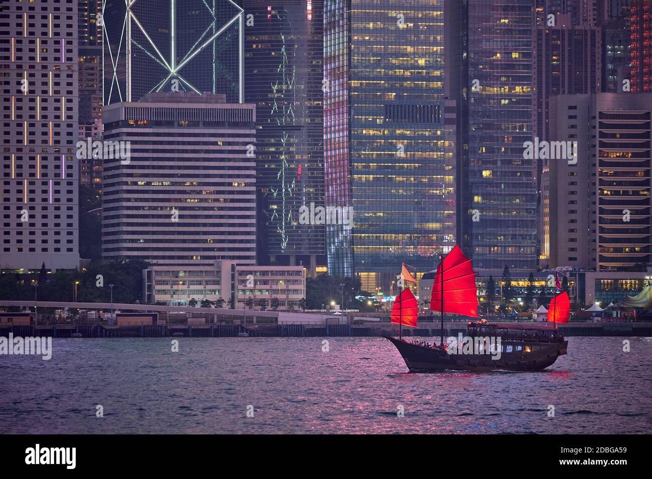 Tourist junk boat ferry with red sails and Hong Kong skyline cityscape ...