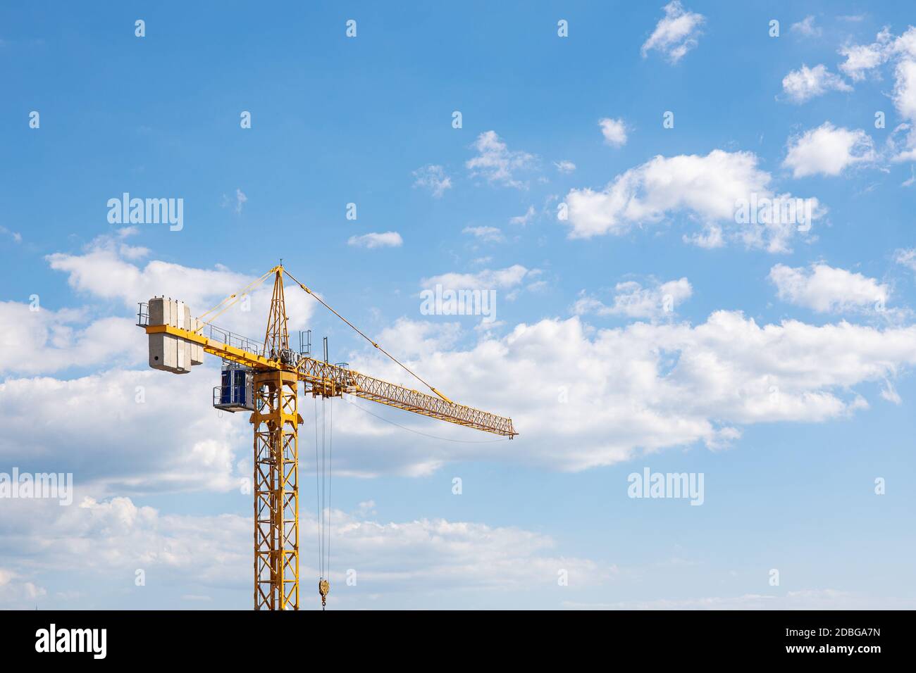 Yellow tall construction crane against the background of blue sky and ...