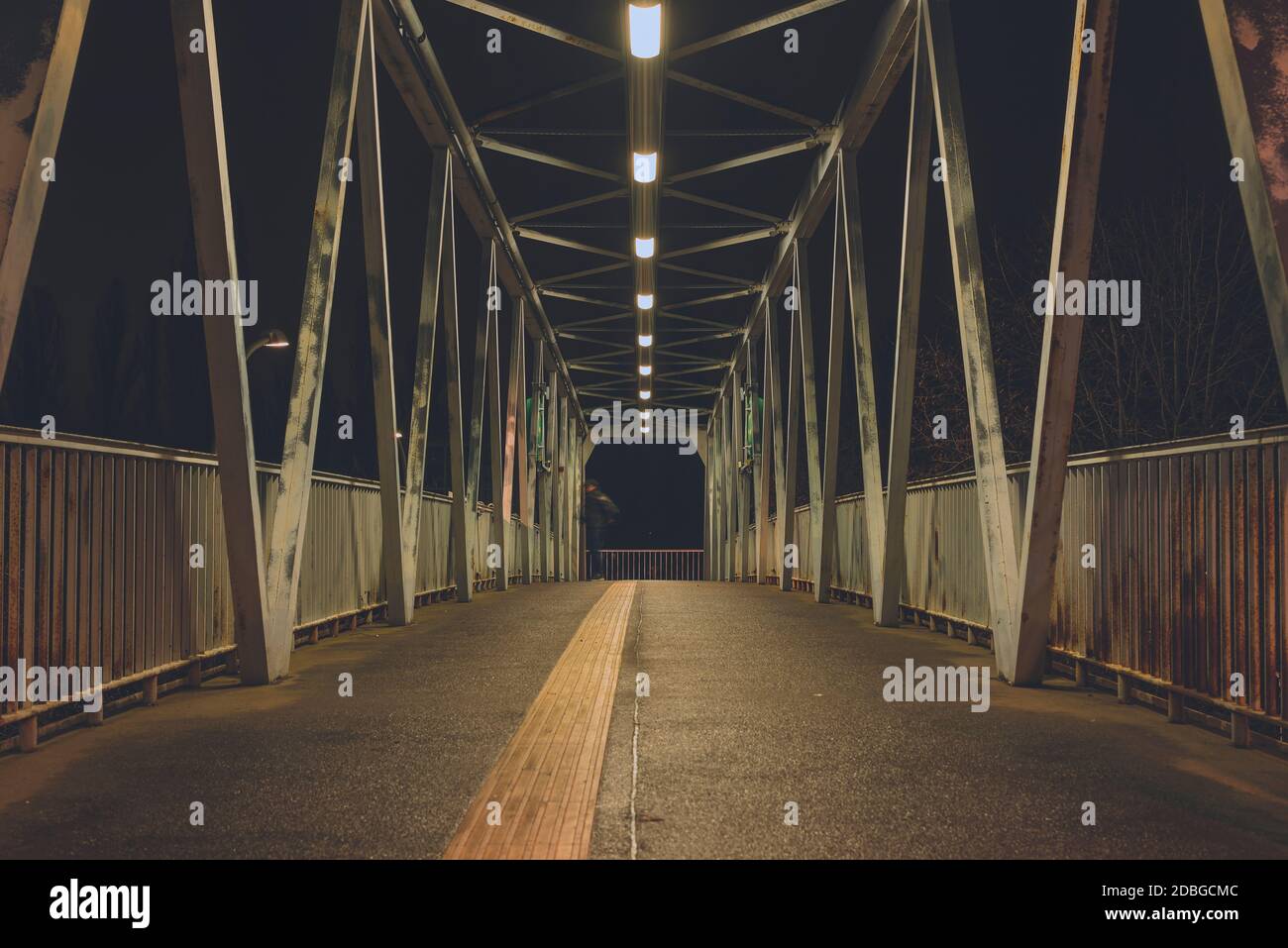 A steel bridge for pedestrians at night, an illuminated pedestrian ...