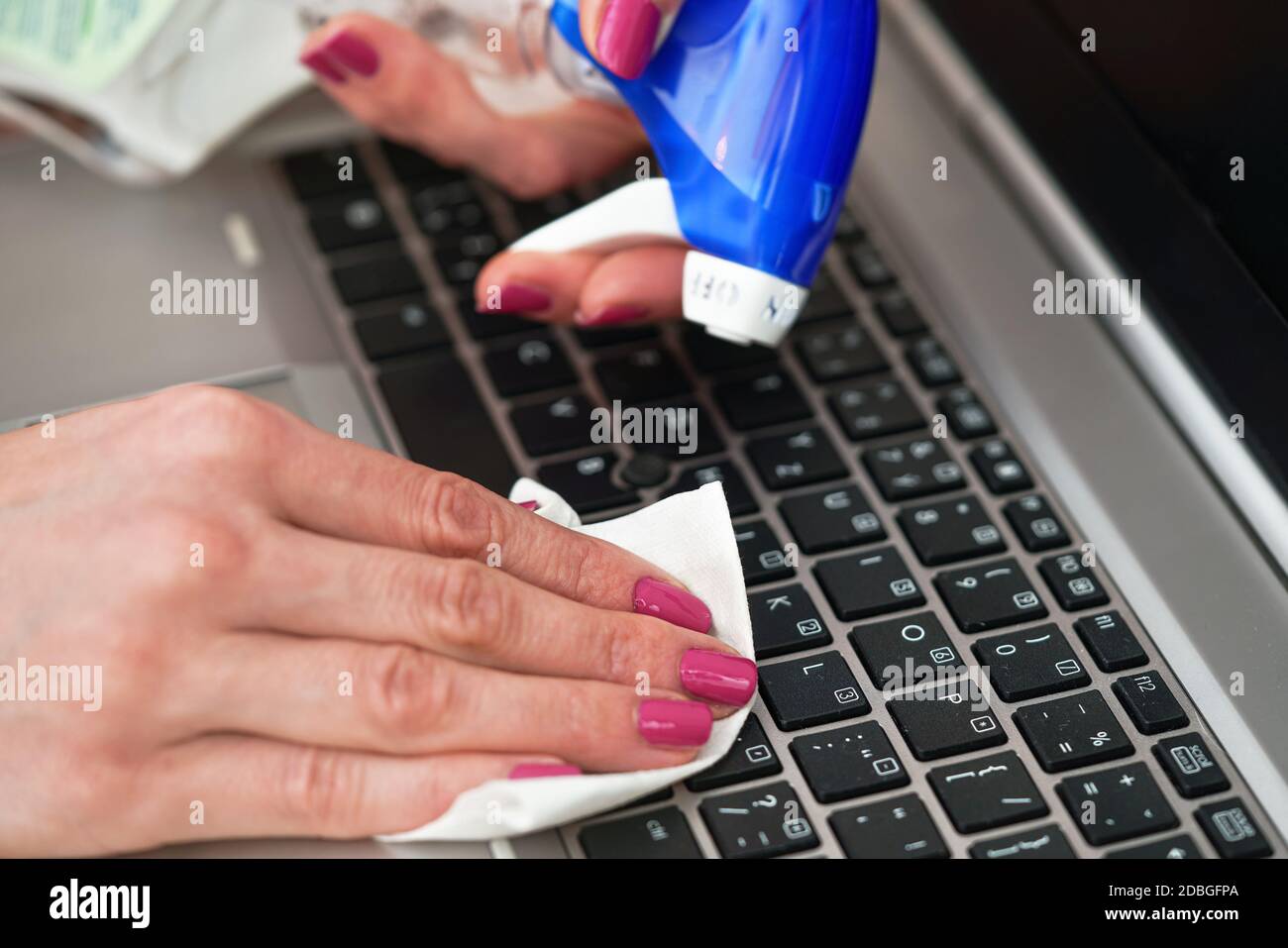 Woman cleaning laptop keyboard with white tissue, detail on her fingers ...