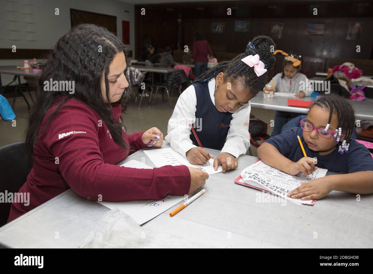 Teacher helps elementary school students work on spelling words at an ...