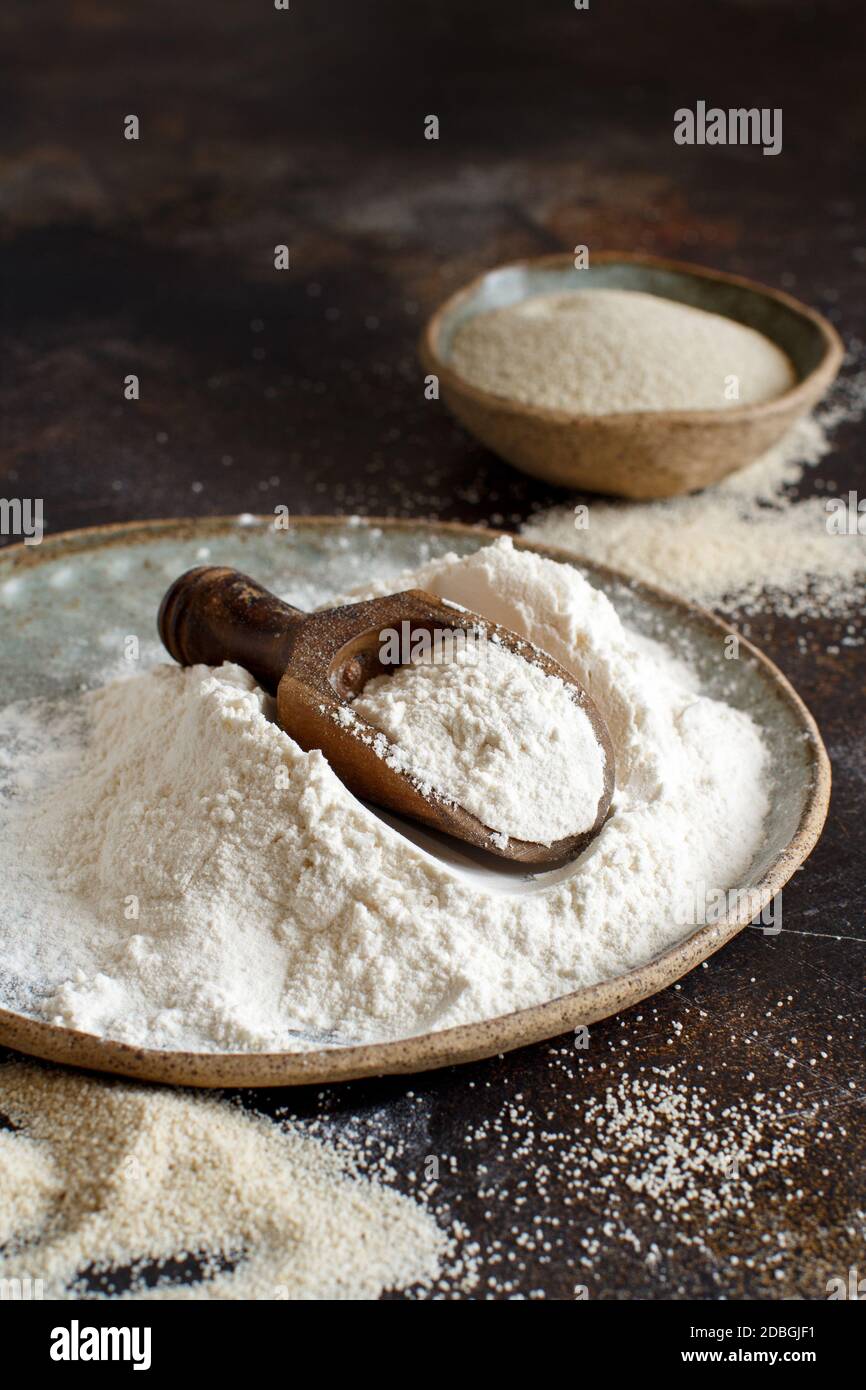 Raw fonio flour and seeds with a spoon on dark background close up ...
