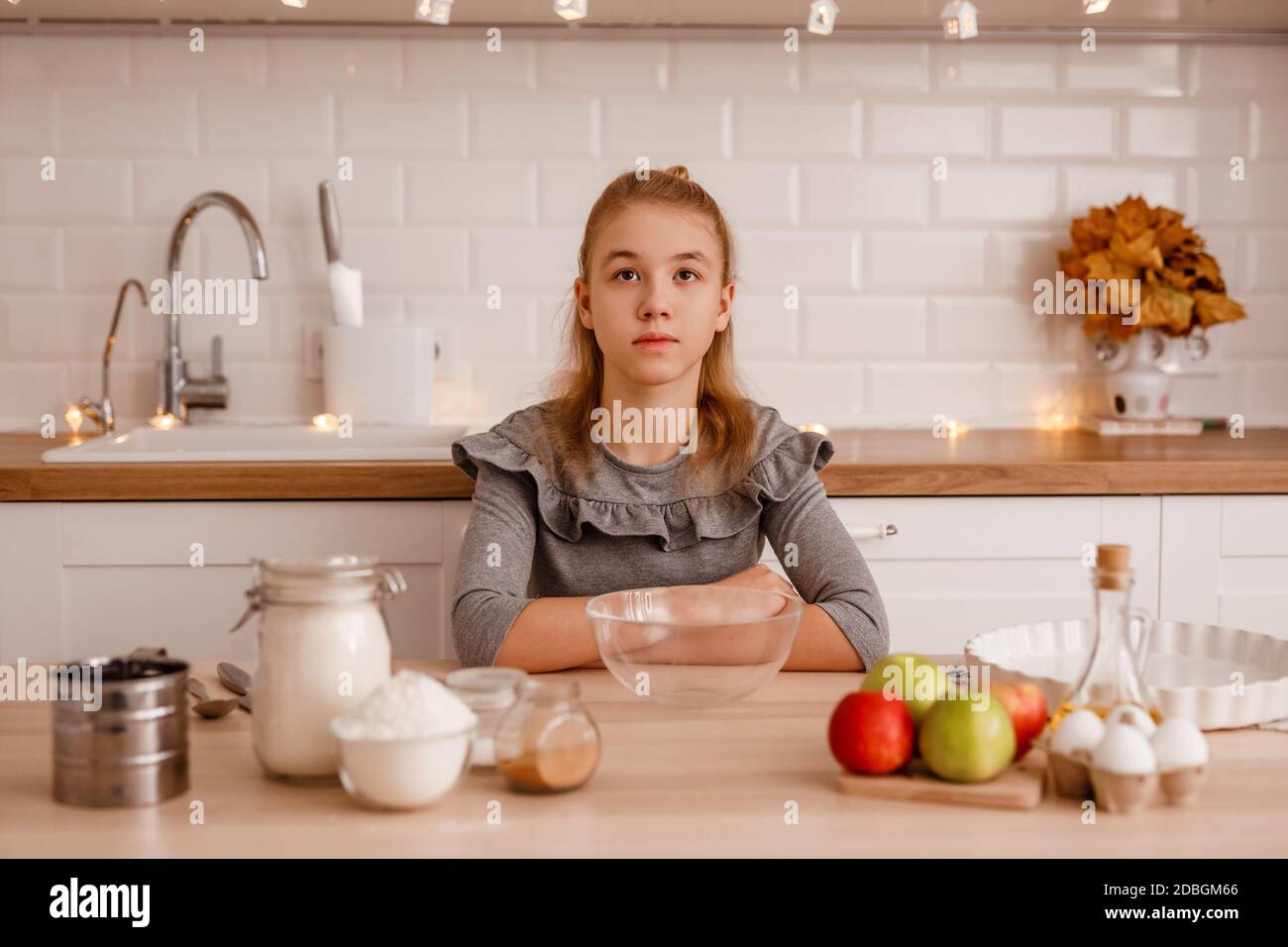 Blonde teenage girl in a gray dress is going to cook traditional apple ...