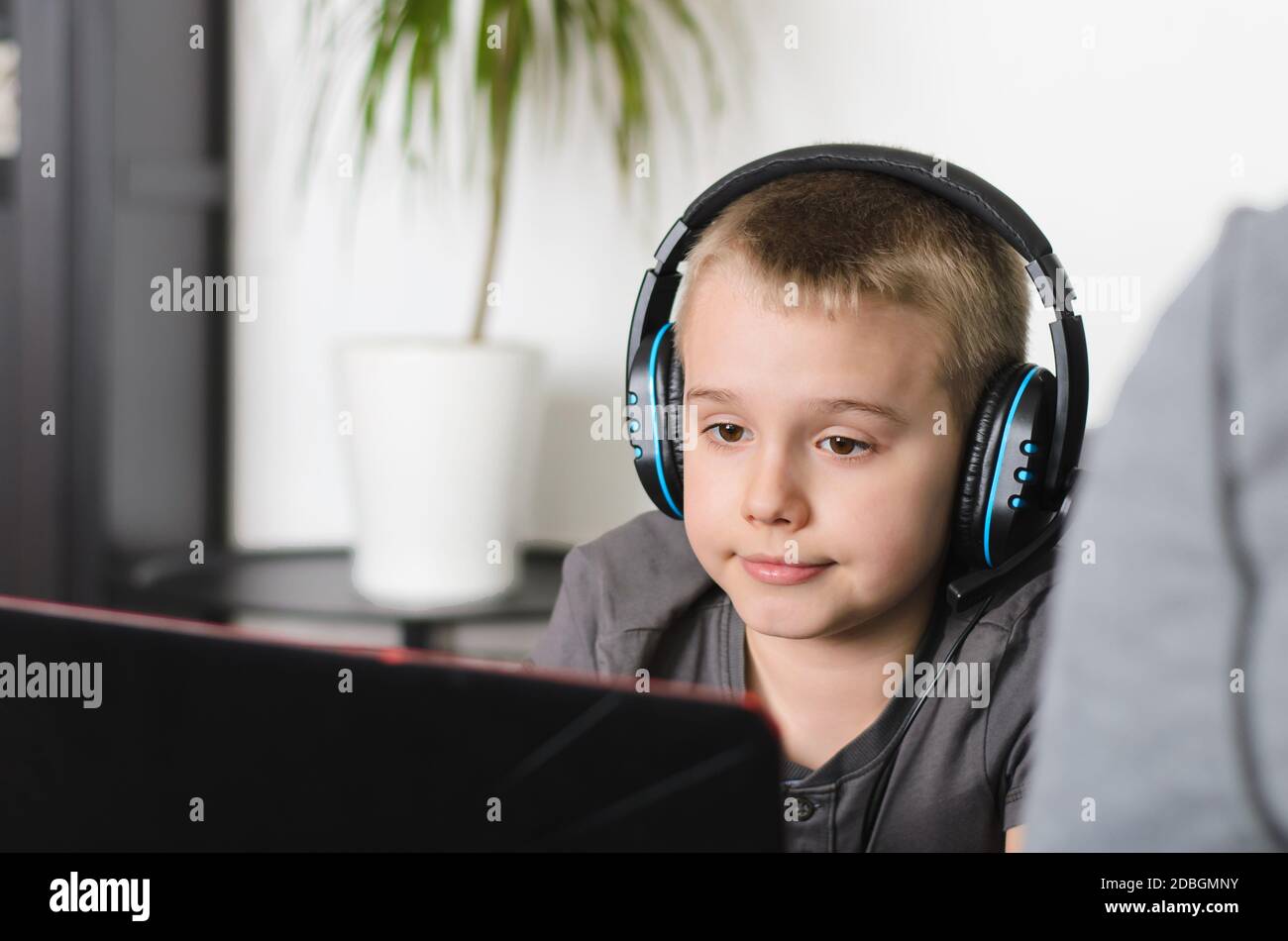 Happy boy in headphones playing online video game on laptop computer at ...