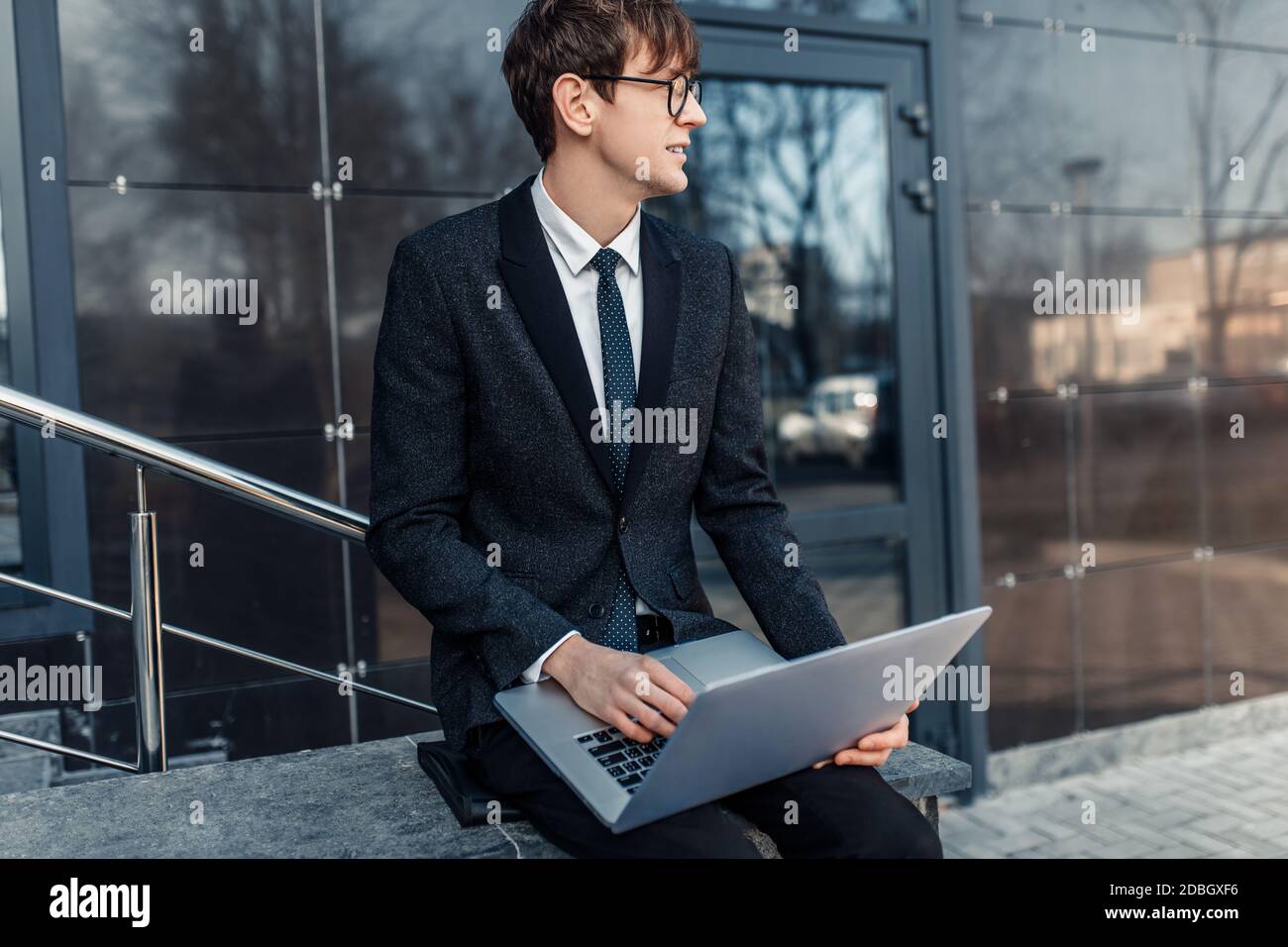 Attractive young businessman in a business suit, using a laptop for ...