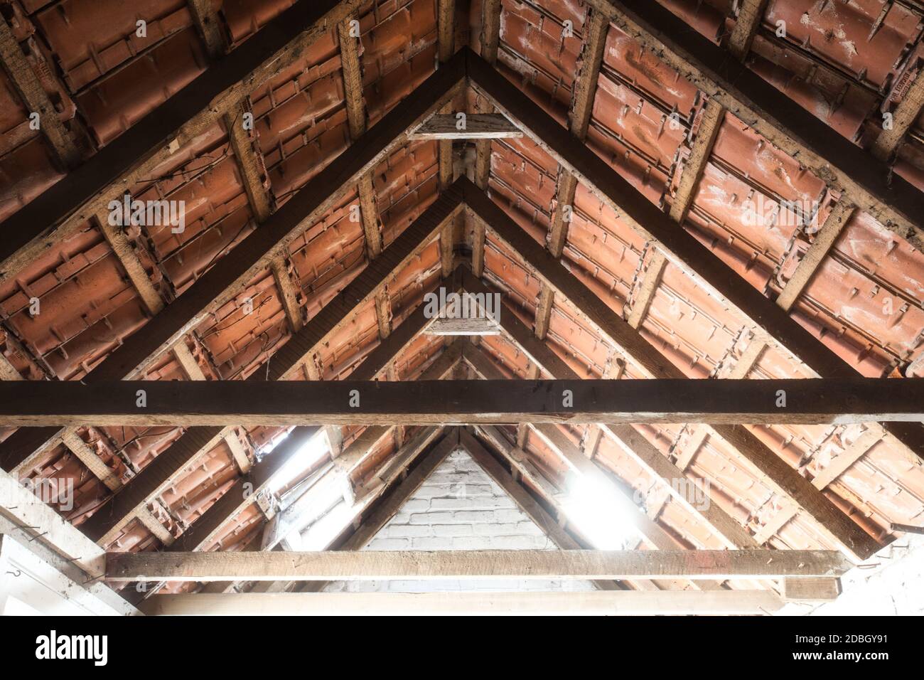 Looking up at the ceiling of an old barn with old roof tiles and wooden ...