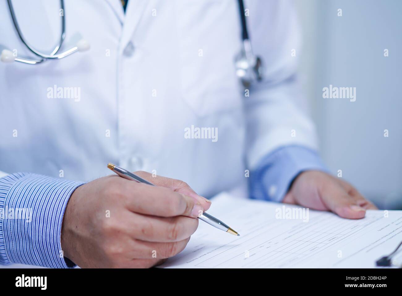 Doctor writing down the diagnosis on clipboard while Asian senior or ...