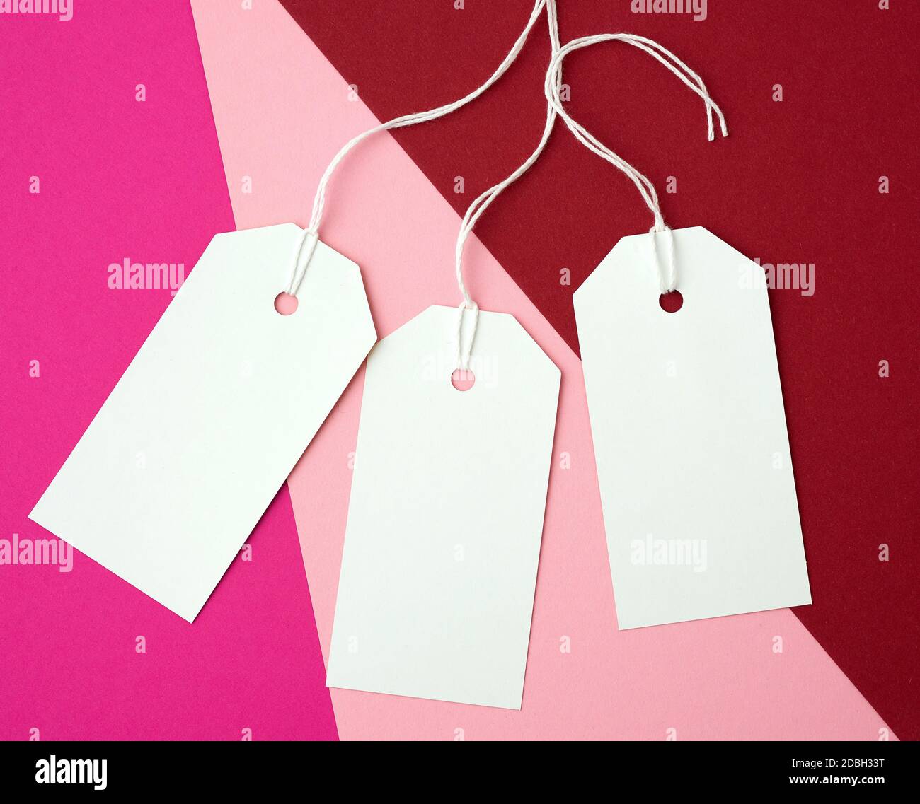 three white paper rectangular tags on a rope on a colored background ...