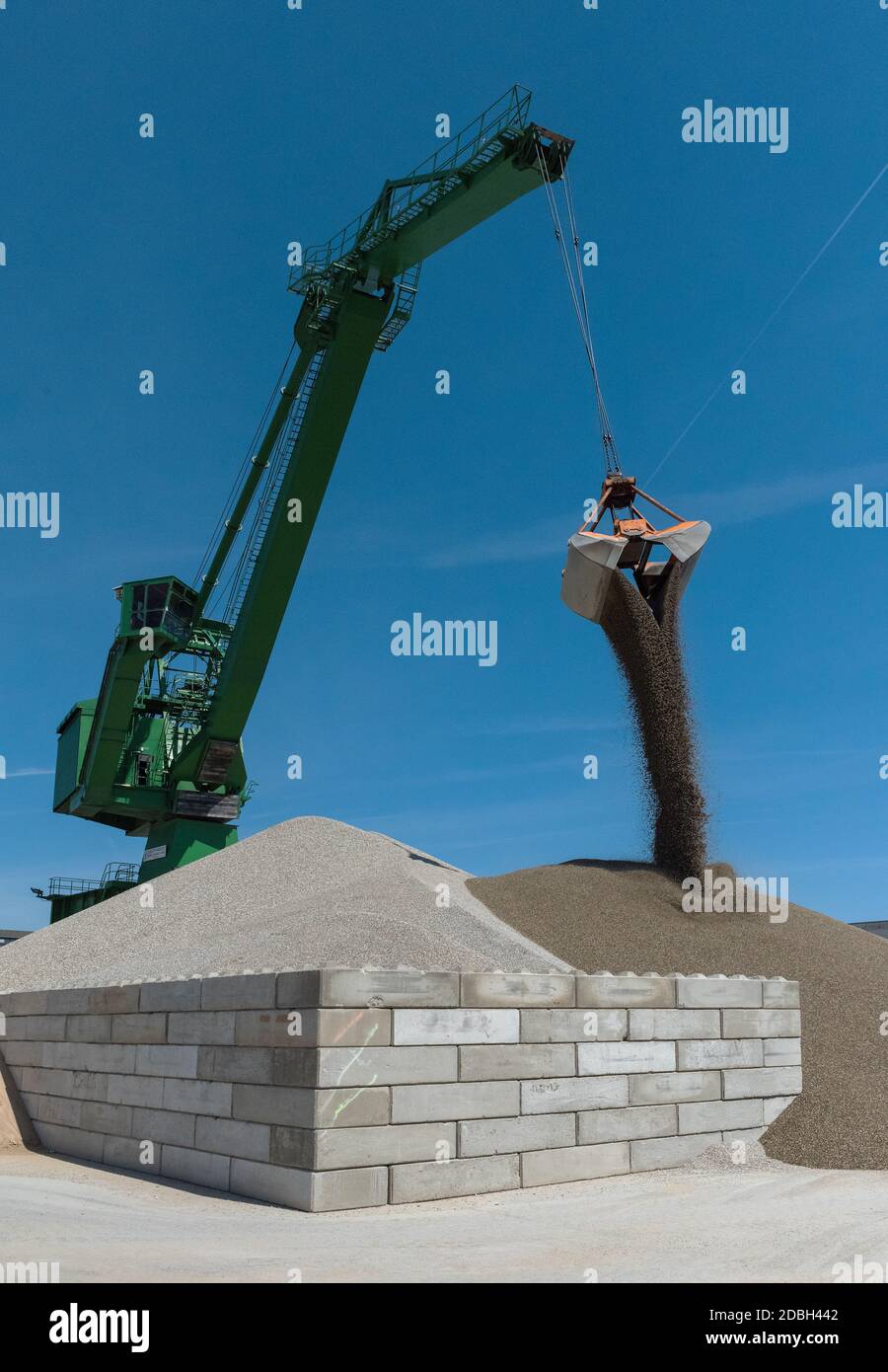 Green harbor crane pours sand and gravel onto a hill Stock Photo - Alamy