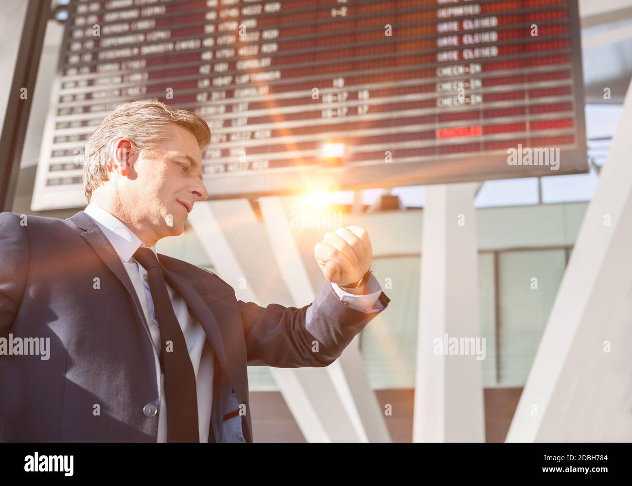 Portrait of mature businessman checking time on his watch while waiting ...
